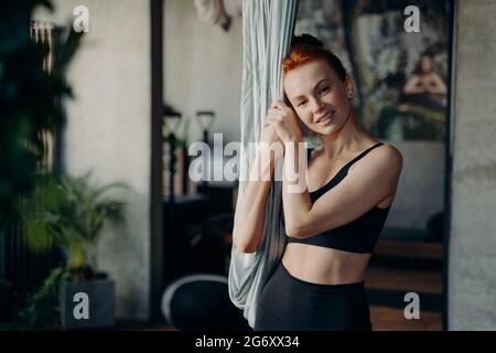 Pleasant-looking red haired yoga instructor in a turtleneck doing ...