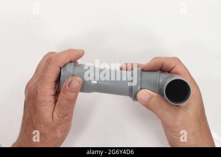Closeup of a man holding plastic fittings, bends, and joints for ...