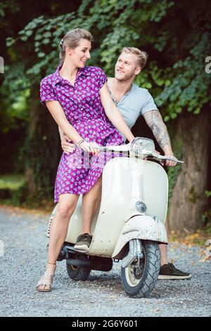Woman sitting on retro scooter or motor bike in red color, traveling in mountains on island ...