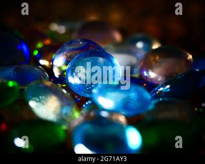 Closeup of fun vibrant glass gems reflecting bright lights on a ...