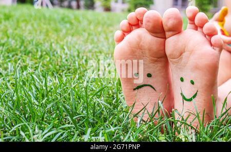 Baby feet with paint pattern are smiling and sad on the green grass ...