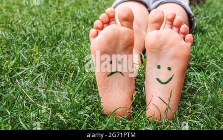 Baby feet with paint pattern are smiling and sad on the green grass ...