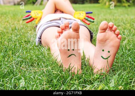 Baby feet with paint pattern are smiling and sad on the green grass ...
