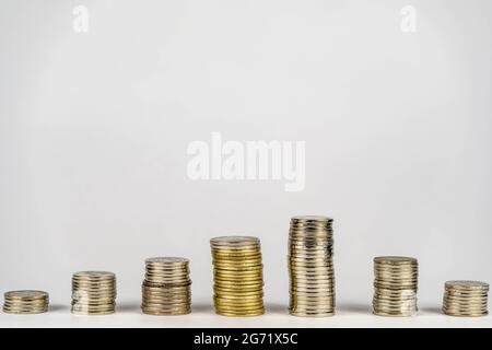 Seven stacks of golden coins with different heights arranged in growing ...