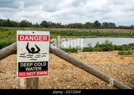 Sign warning of deep cold water in a flooded pit at Clee Hill Quarry in ...