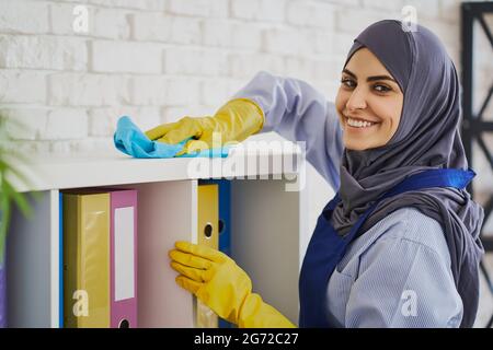 Young pretty Muslim woman with glass of coffee resting in chair and ...