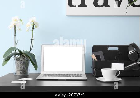 Comfortable workplace with modern laptop and orchid flower near color ...