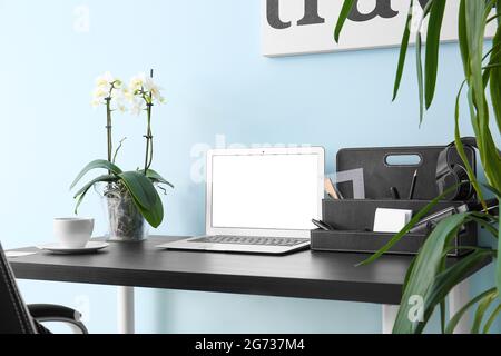 Comfortable workplace with modern laptop and orchid flower near color ...