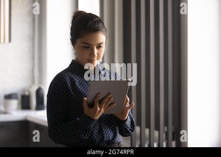 Focused young Indian tablet user woman relaxing on sofa Stock Photo - Alamy