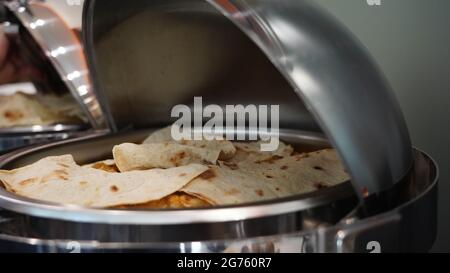 A closeup shot of fresh tortillas covering the meat in a cooking pot ...