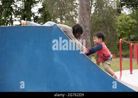 The older Malaysian child helping younger child up the ramp while ...