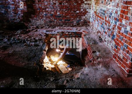 Archaeologist with flashlight examines the old crypt under church Stock ...