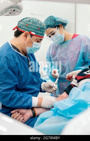 Smiley doctor working in clinic drawing blood to faceless patient. He ...