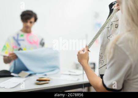 fashion designer holding tissue sample and writing in notebook near ...
