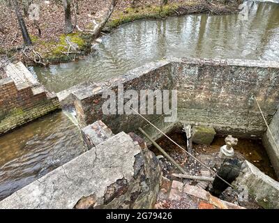 Dam concrete wall and valves with river flowing in a forest in rural ...