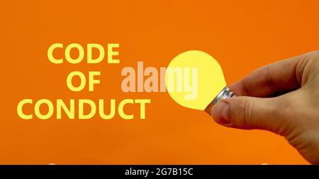Code of conduct symbol. Businessman holds yellow shining light bulb ...
