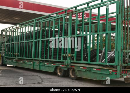 A green cage trailer on a semi truck with black plastic tubing in rolls ...