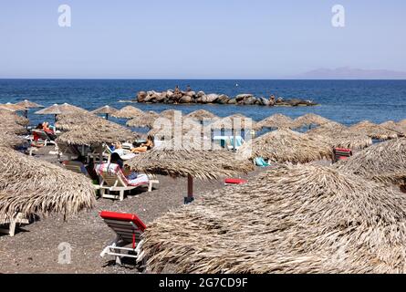 Kamari, Santorini, Greece - June 27, 2021: Sun loungers on the black ...