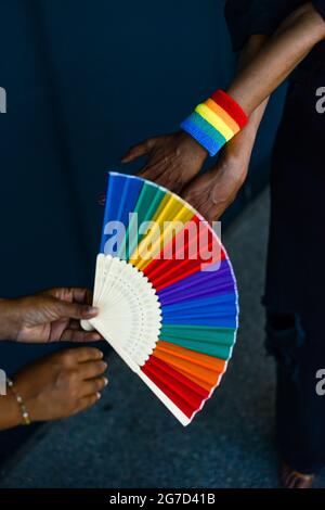 Hands hold LGBTQ pride fan and wristband Stock Photo - Alamy