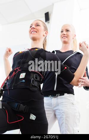 Female personal trainer giving man ems electro muscular stimulation ...