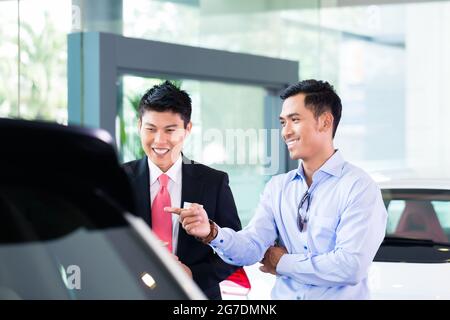 Asian Car Salesman selling auto to customer Stock Photo - Alamy