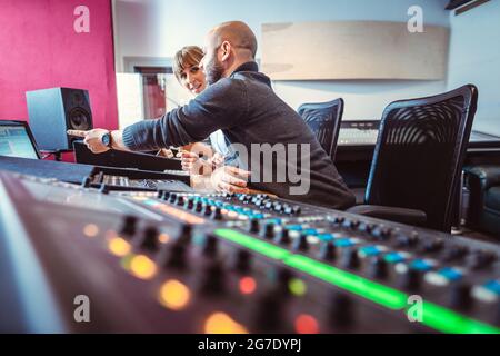Sound engineer and singer or musician discussing the mix of a ...