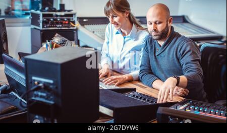 Singer or artist and sound engineer working in the studio at a ...