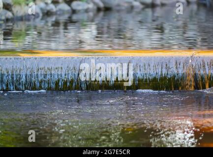 Cold transparent water of decorative artificial waterfall in summer ...