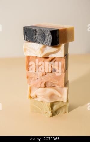 Vertical shot of stacked handmade bars of hand soap on a brown surface ...