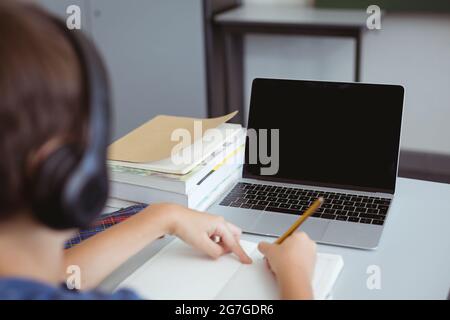 Education and e-learning. Little schoolboy with laptop in classroom ...