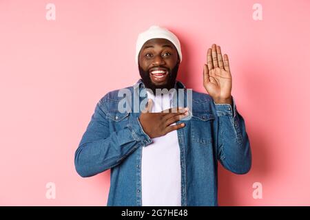Image of handsome smiling guy telling the truth, raising on arm to ...