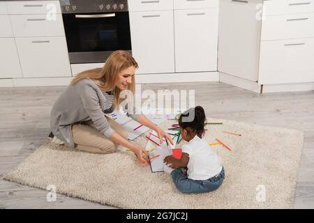 happy mother drawing with adopted african american girl while sitting ...