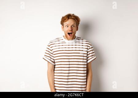 Special promotion concept. Amazed redhead male model gasping, staring ...