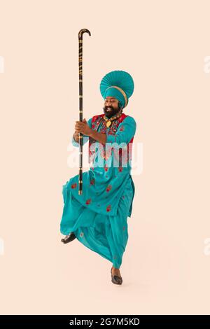 A man in Bhangra costume holding the Khunda Stock Photo - Alamy