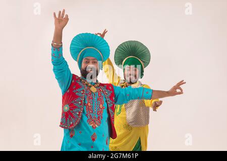 Two Bhangra dancers performing a dance step together using Khunda Stock ...