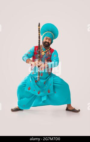 A Bhangra dancer holding a Khunda in his hand Stock Photo - Alamy