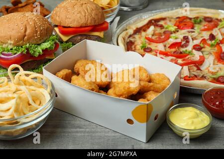 Different fast food on gray textured table Stock Photo - Alamy