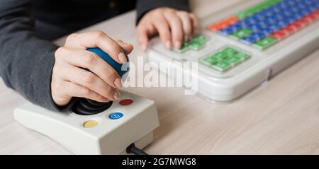 An unrecognizable woman with cerebral palsy is typing on the keyboard ...