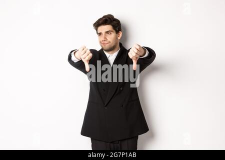 Skeptical and displeased man in black suit, looking away reluctant ...