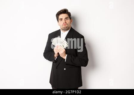 Image of greedy guy in black suit, holding money and unwilling to share ...