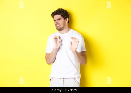 Digusted guy refusing and grimacing, looking at something with aversion ...