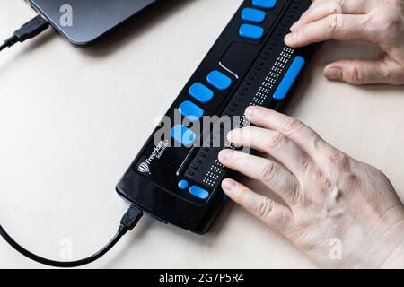 Moscow, Russia - June 5, 2021: fingers read with Focus 40 Blue Braille ...