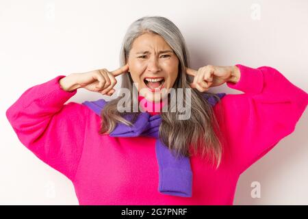 Portrait of asian woman shut ears and feeling discomfort from loud ...