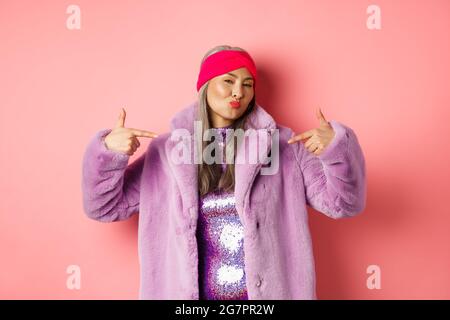 Fashion and shopping concept. Cool asian senior woman pointing fingers ...