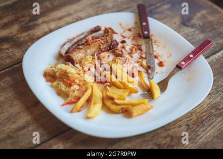 Leftover food on place after partying.Closeup fork,knife on the plate ...