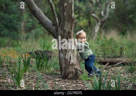 Australian kid hiding behind a tree Stock Photo - Alamy