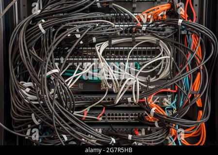 A computer network server cabinet with a mess of tangled blue coloured ...