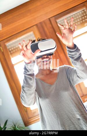 curly young woman in 3d glasses eating popcorn while holding bucket ...