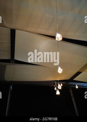 A closeup of small light bulbs hanging in a dark room Stock Photo - Alamy