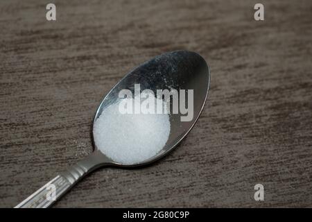 a silver metal spoon with too much salt in it on a marble table ...